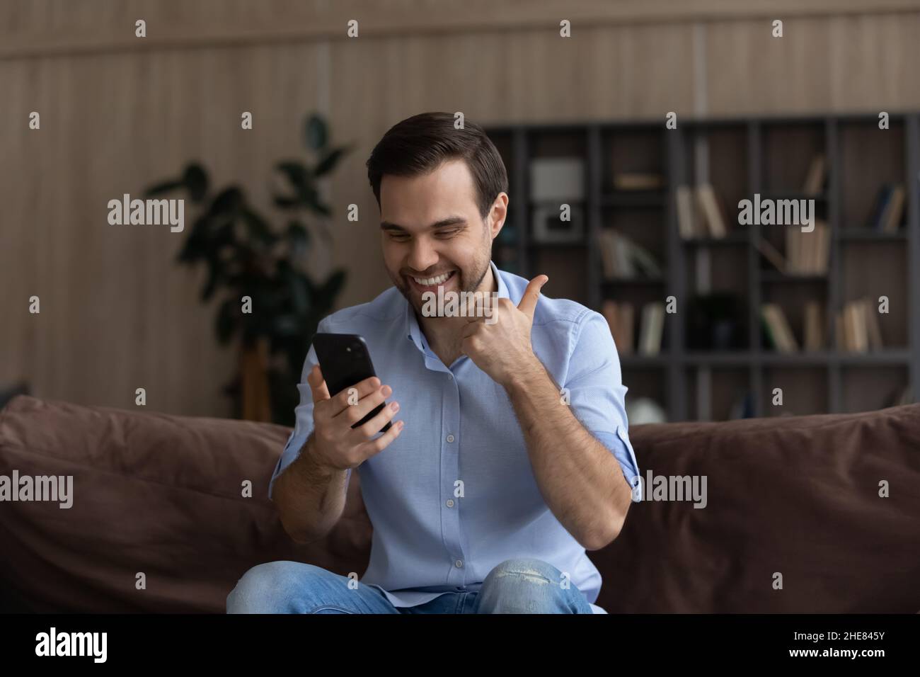 Excited man looking at phone screen, showing thumb up gesture Stock ...