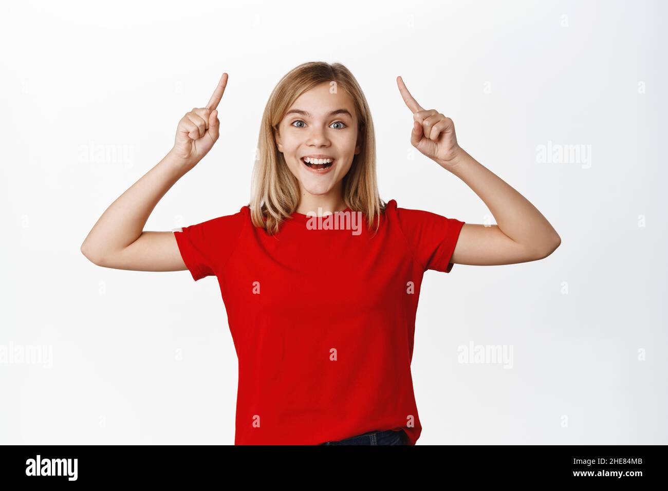 Happy smiling little girl, child pointing fingers up and smiling amazed ...