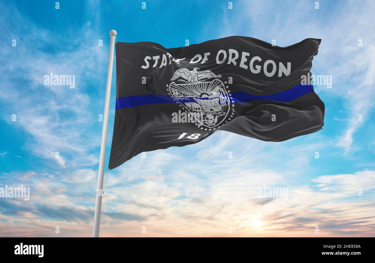 blue line flag of Oregon state, Usa at cloudy sky background on sunset ...