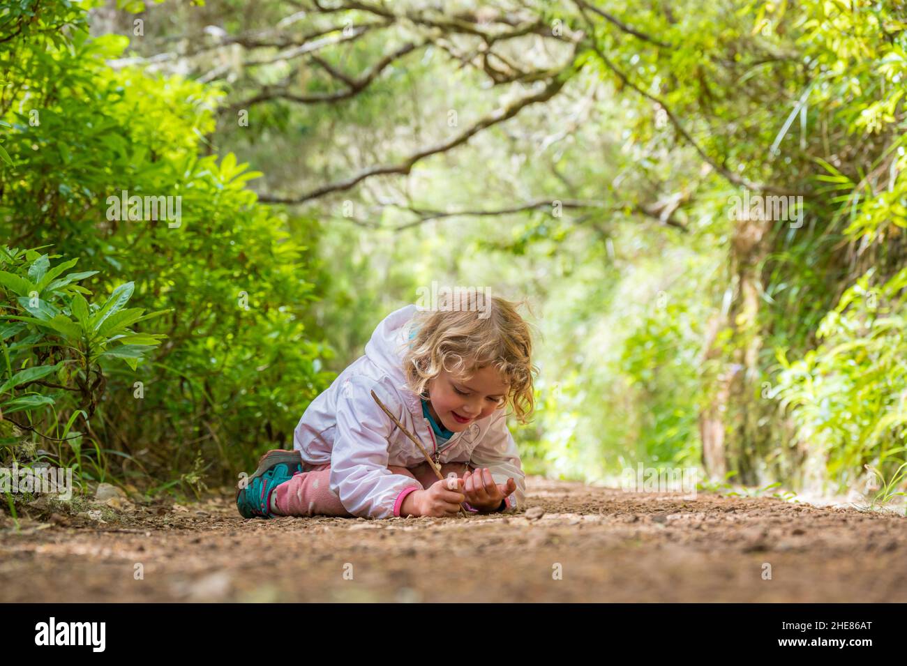 Cute blonde girl sitting on forest trail enjoying the nature and posing ...