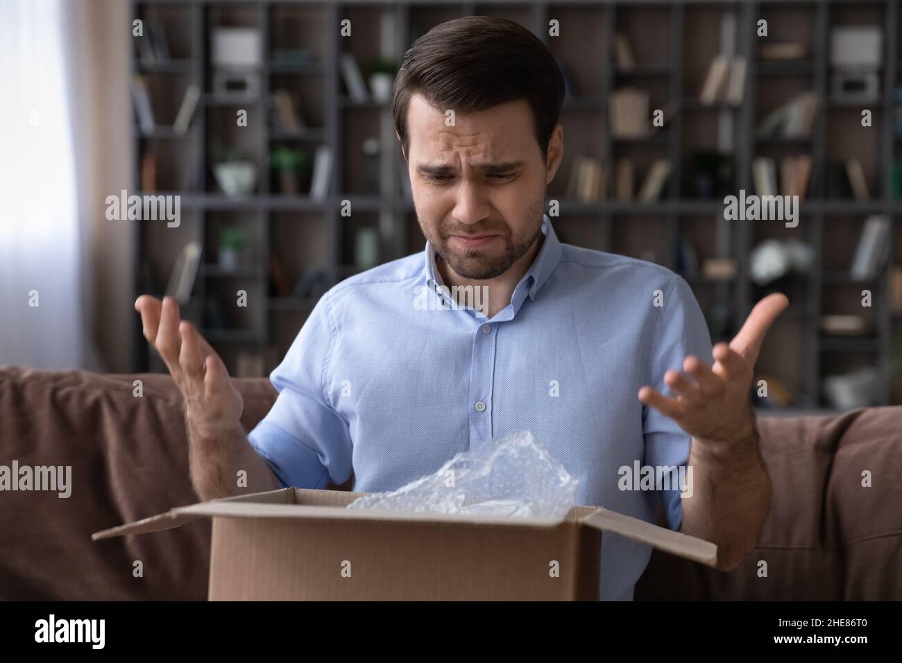 Head shot unhappy dissatisfied man opening parcel at home Stock Photo ...