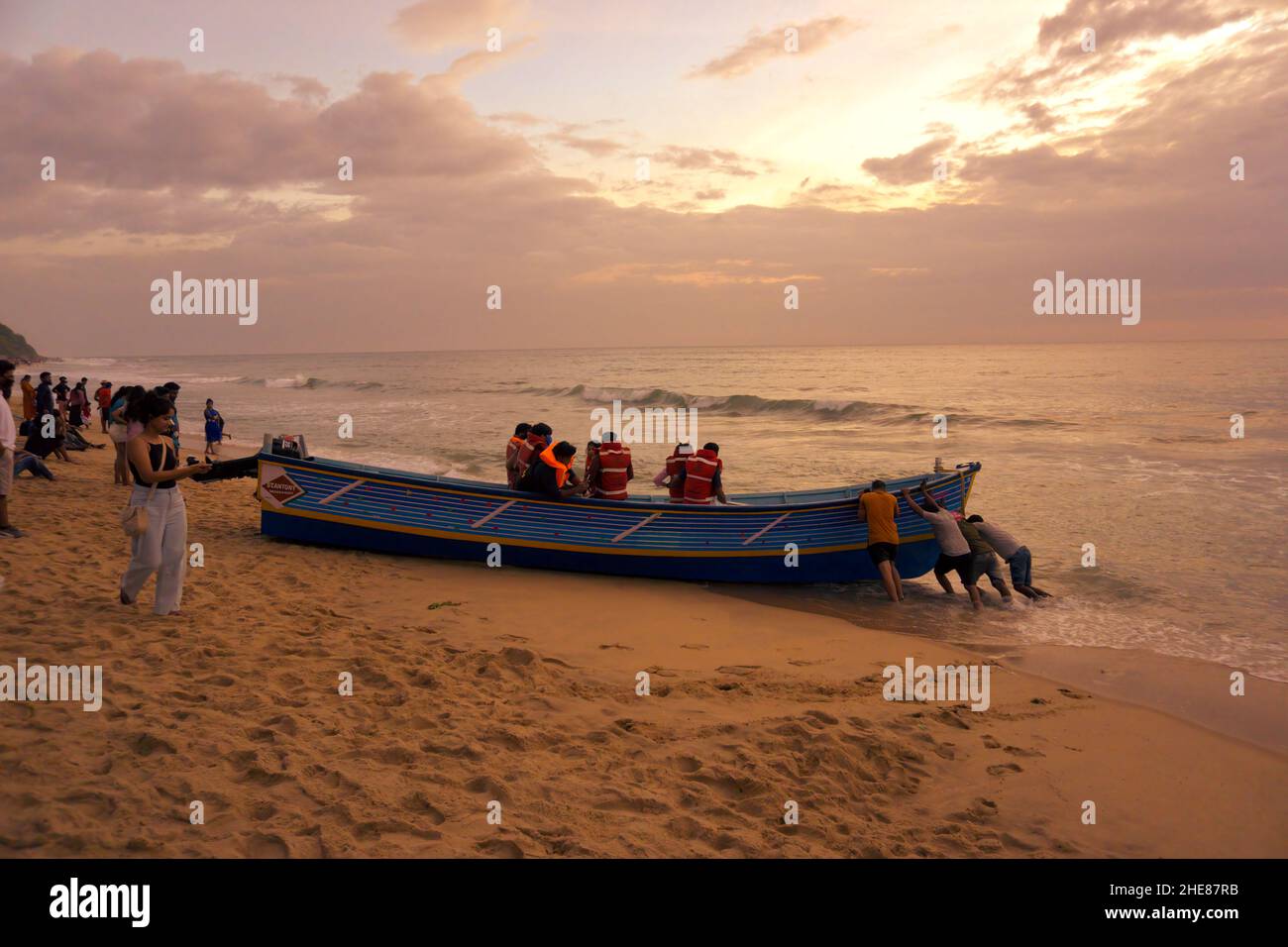 VARKALA, KERALA, INDIA - DECEMBER 31, 2021: Men pushing the boat to the ...