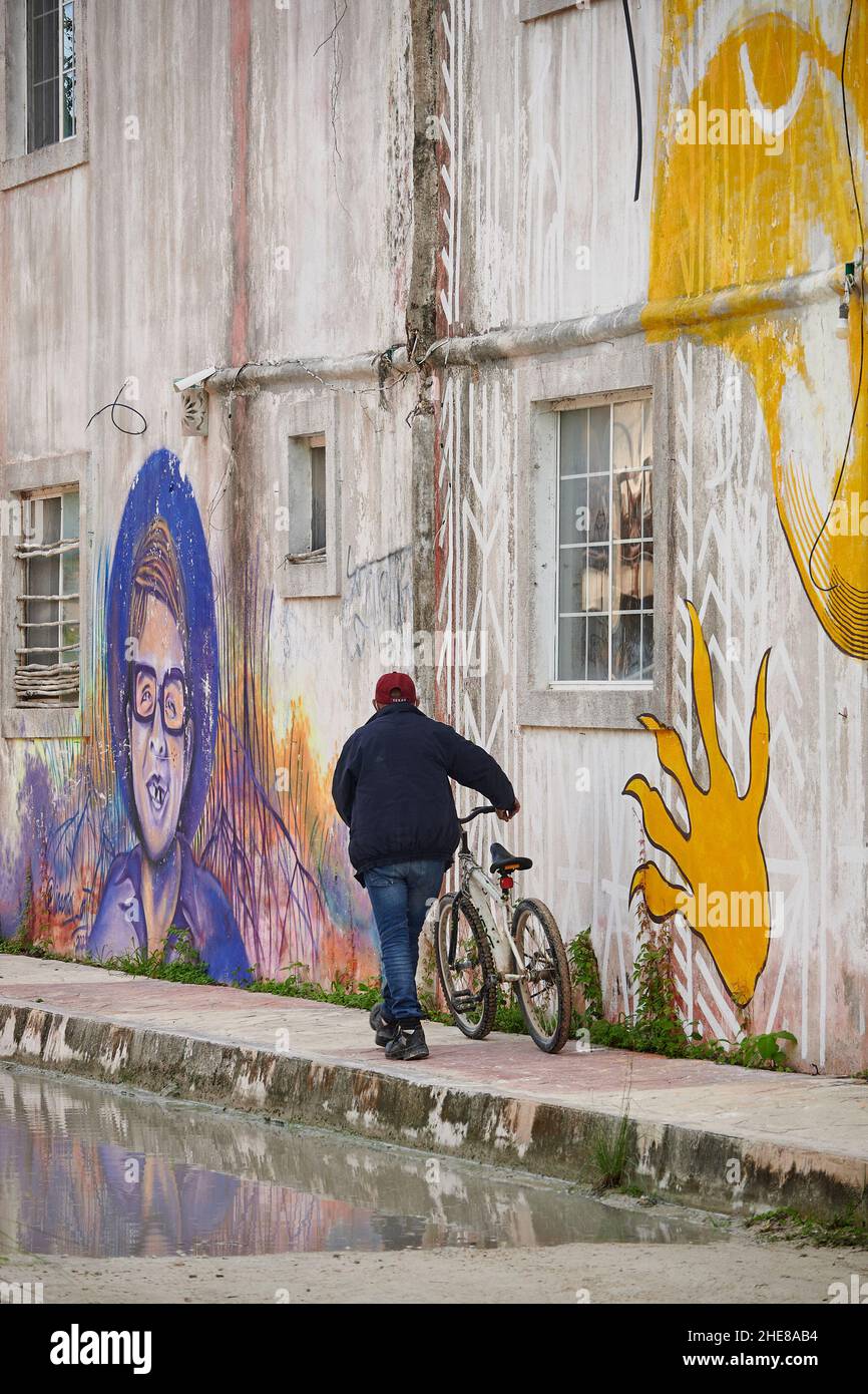 Man walking a bike next to a building with colorful murals in Isla ...