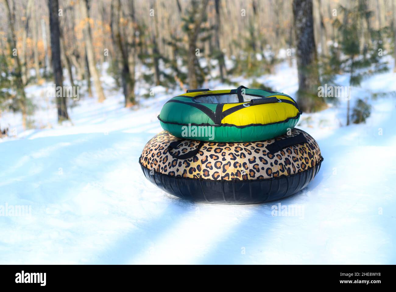 Two donuts for tubing on snow in forest without people. Winter activity ...