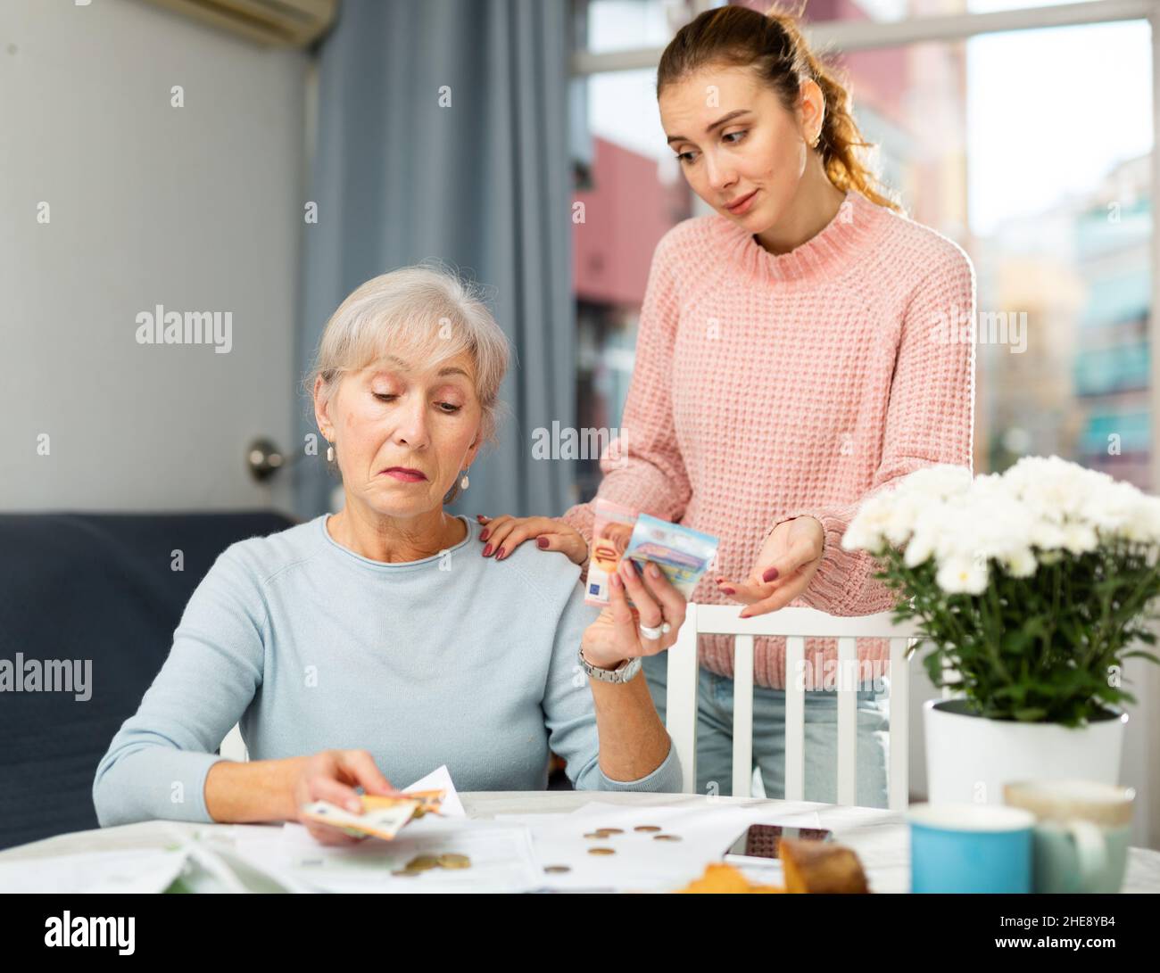 Young woman receiving money from her senior mother Stock Photo - Alamy