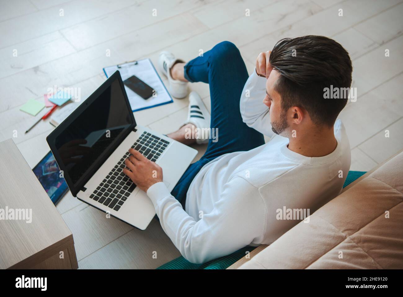 Top view of a man working on laptop computer sitting on the floor with ...