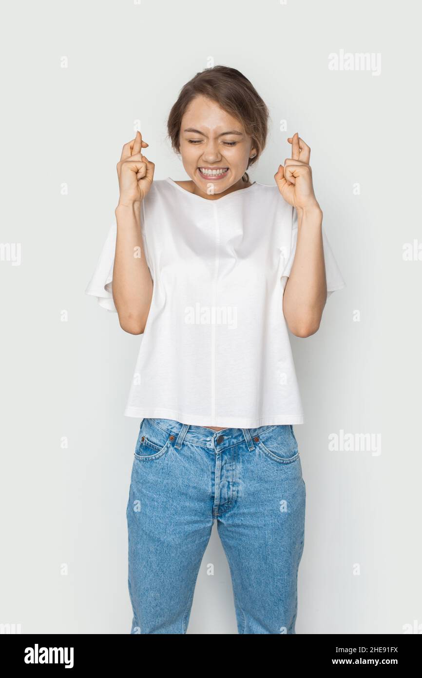 Caucasian woman gesturing with finger crossed smiling with hope and ...