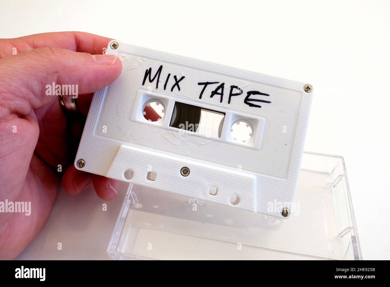 Man's hand holding a white cassette tape with the words MIX TAPE ...