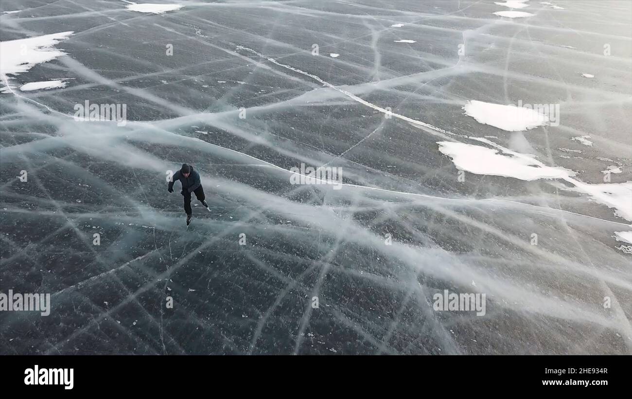 Aerial view of a man skating on lake Baikal covered by ice. Male ...