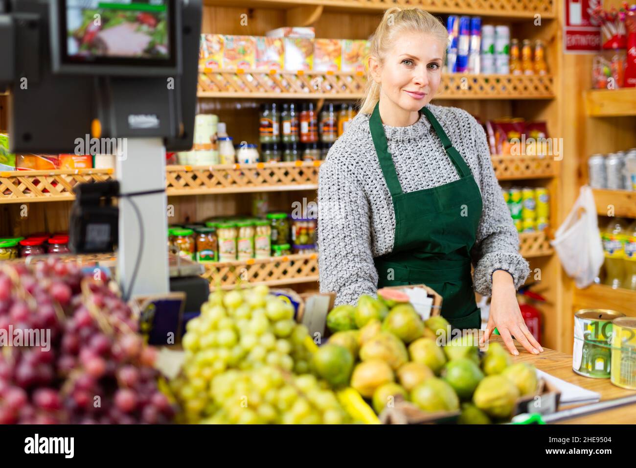 Focused saleswoman working behind counter in grocery store Stock Photo ...