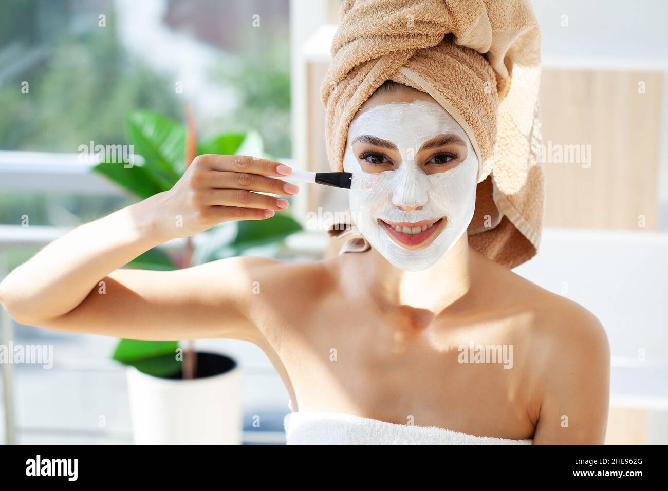 Beautiful Young Woman With Towel Wrapped Around Her Head Applying Face