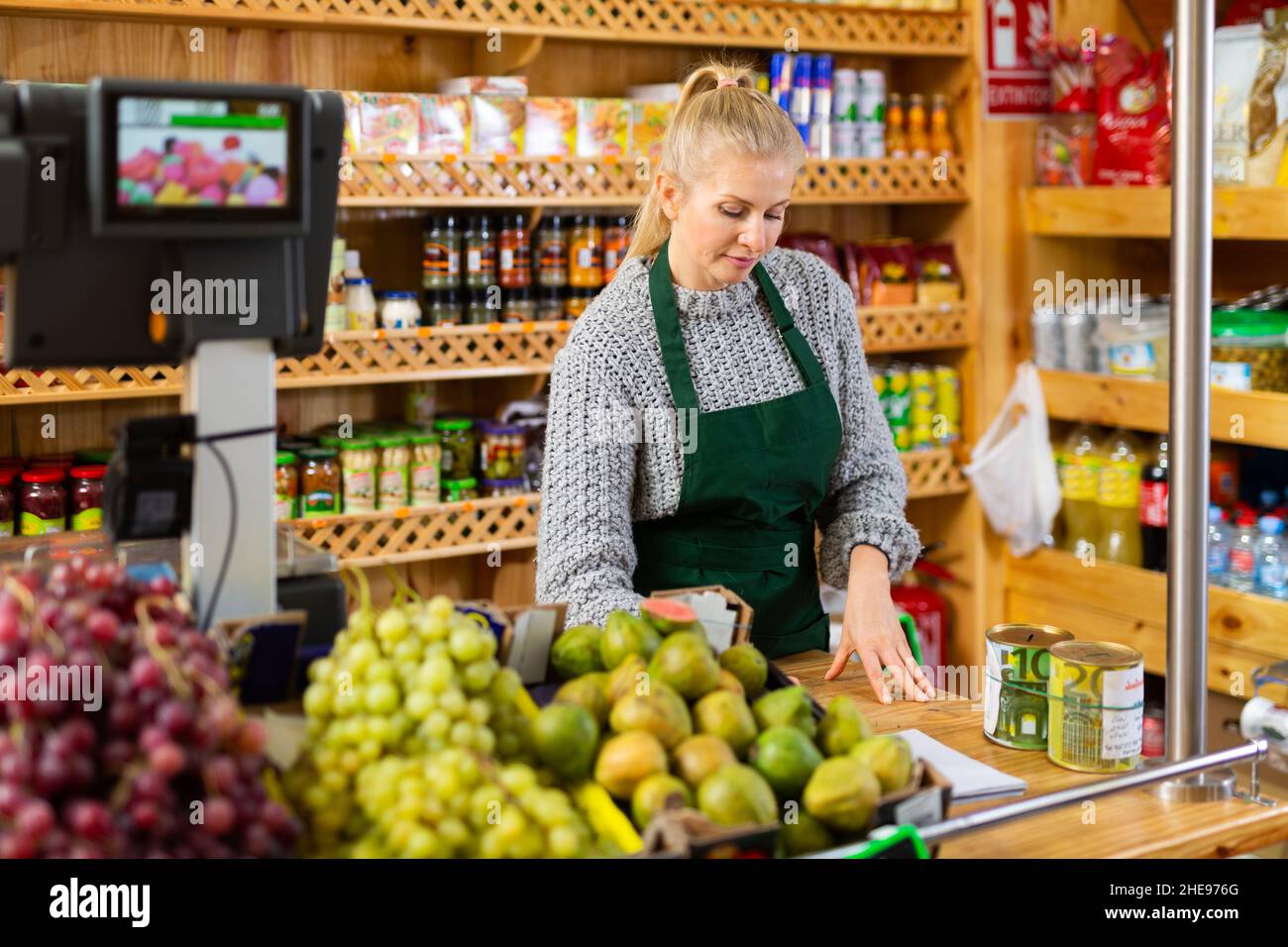 Focused saleswoman working behind counter in grocery store Stock Photo ...