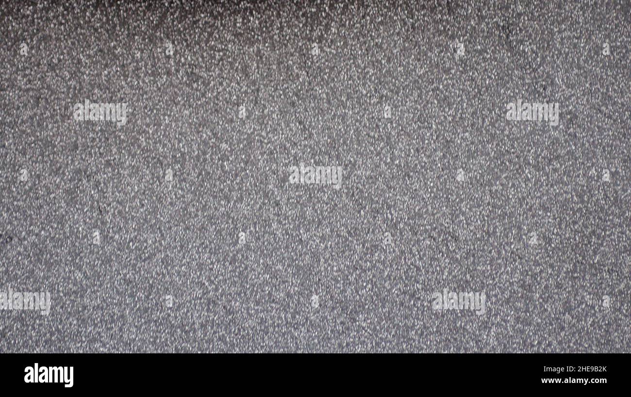 Monochrome black surface with a scattering of small silvery blotches ...