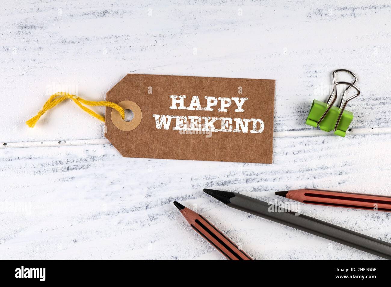Happy Weekend. Cardboard price tag and pencils on a white wooden ...