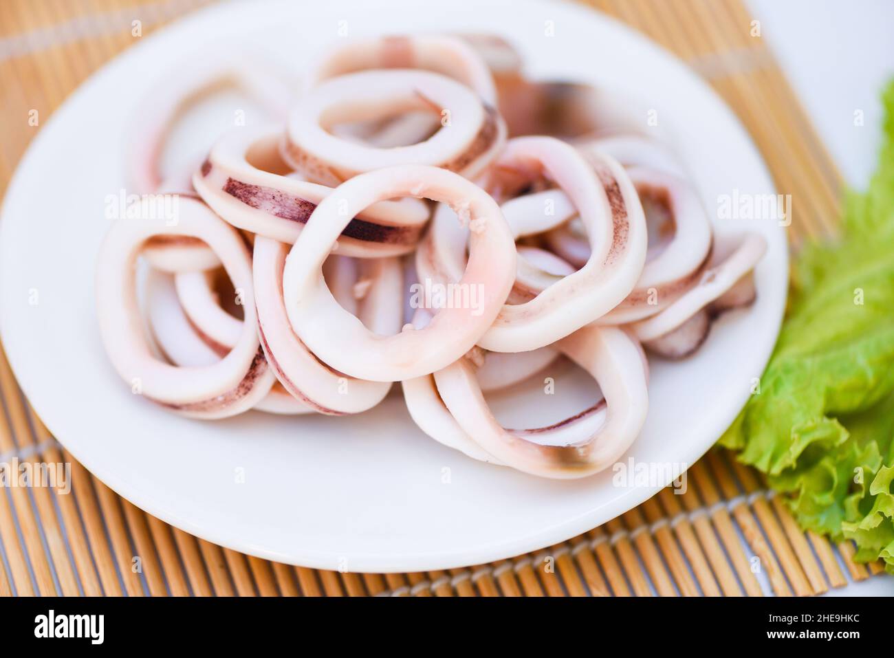 squid rings on white plate, Fresh squid cooked boiled with lettuce vegetable salad on wooden ...