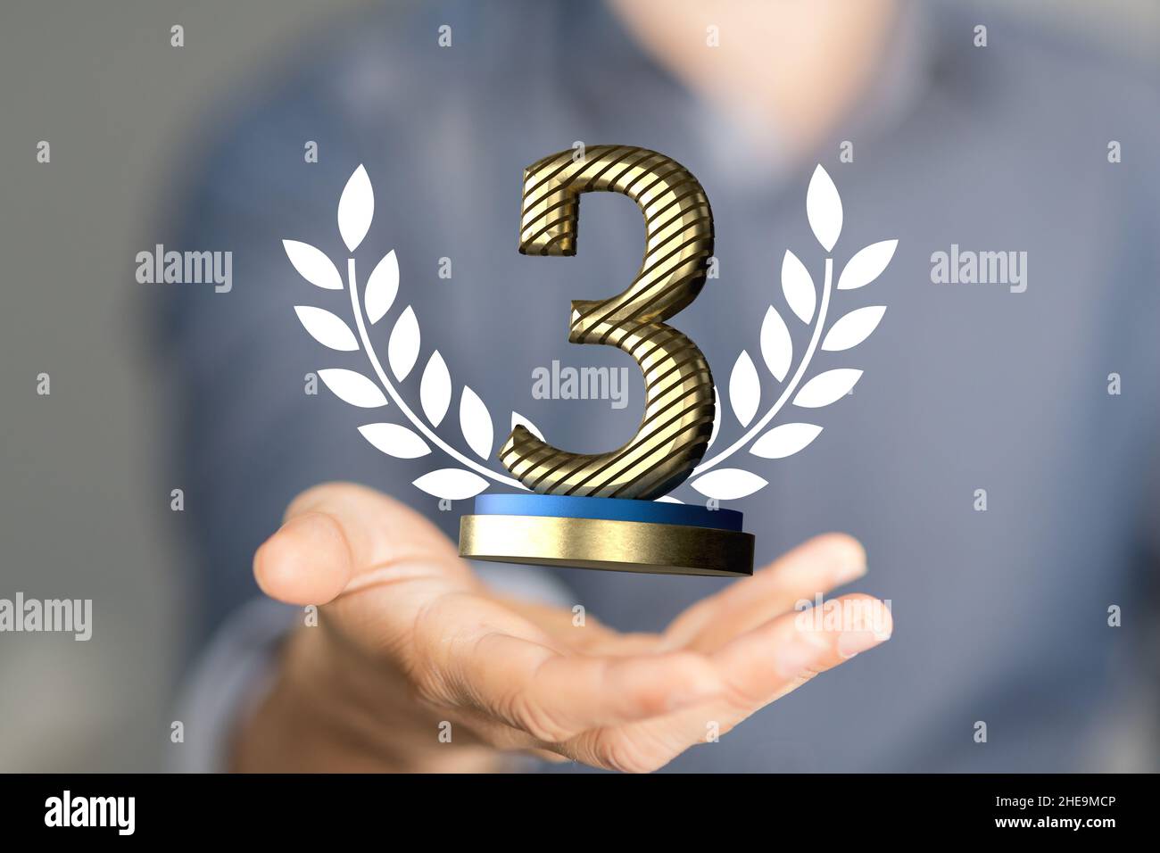 Shallow focus of a human hand holding the 3rd place award, achievement ...