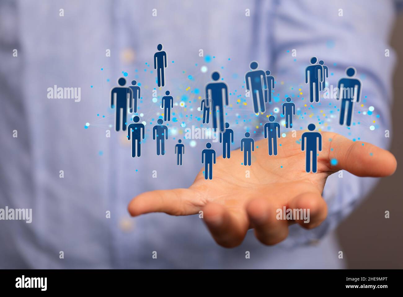 Shallow focus of a human hand holding interconnected human icons for ...