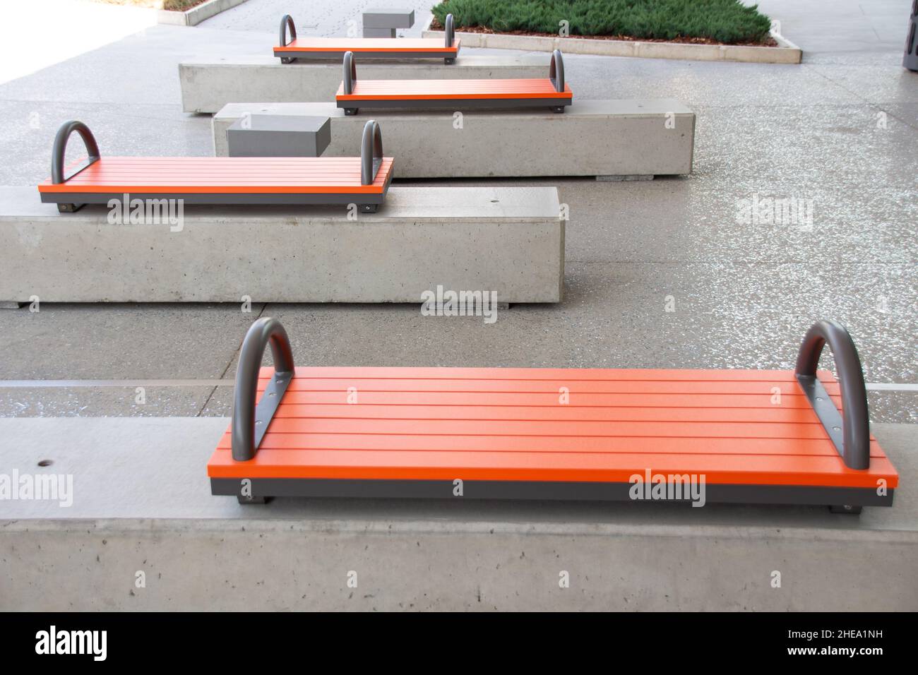 Group of modern orange-colored benches with handles built on stone in ...