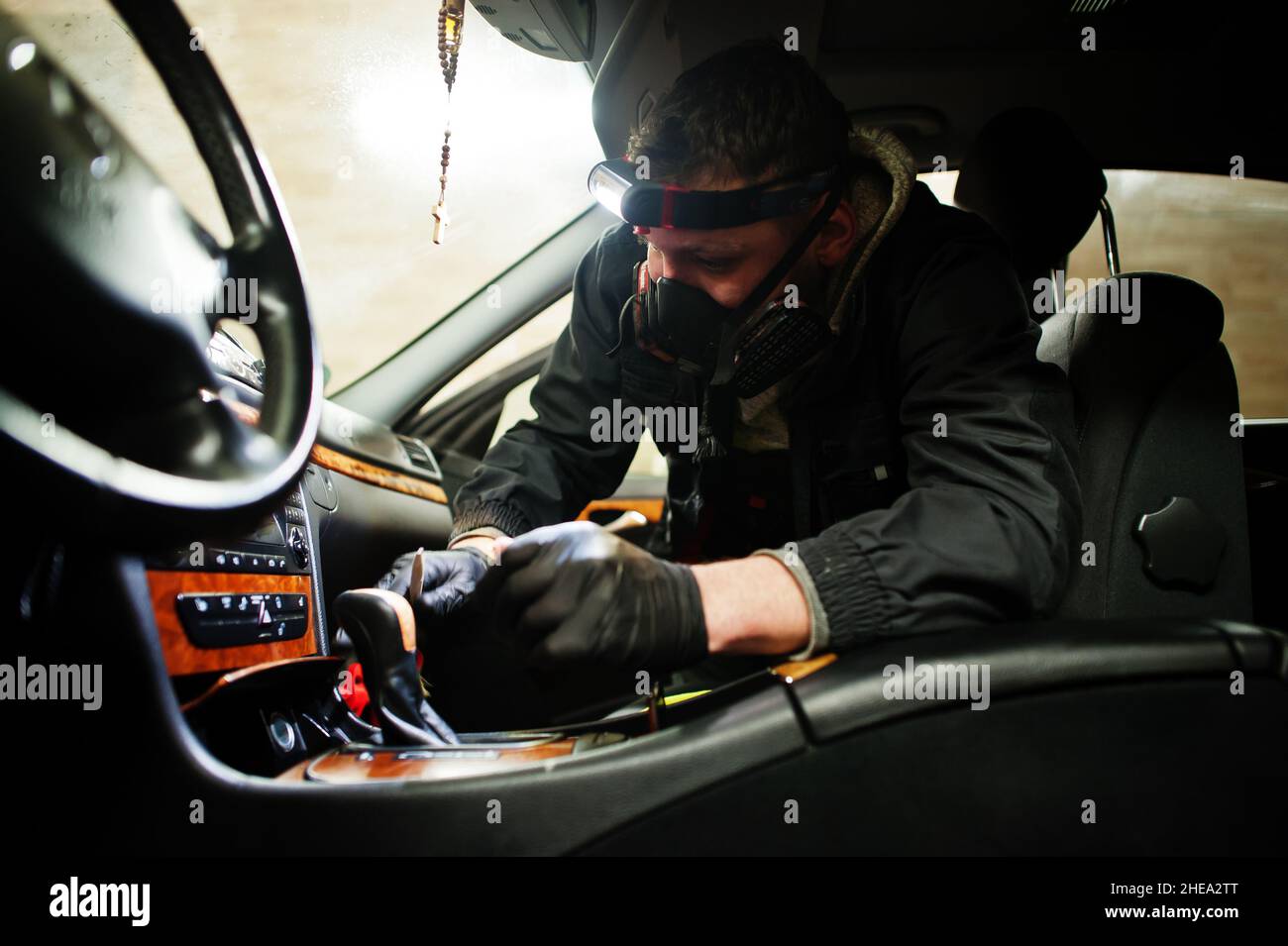 Man in uniform and respirator, worker of car wash center, cleaning car ...