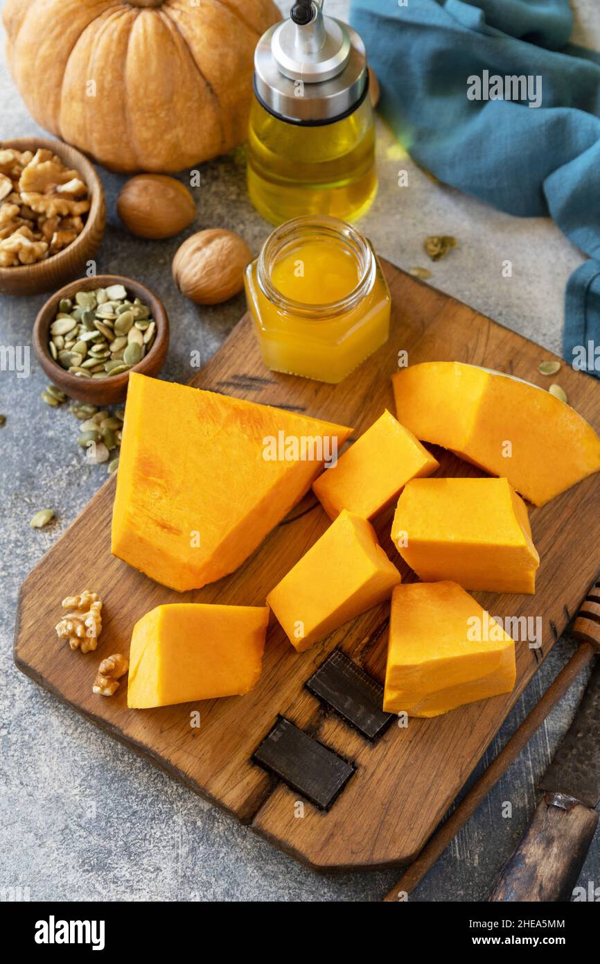 Raw pumpkin, honey, pumpkin seeds and nuts over gray stone background ...