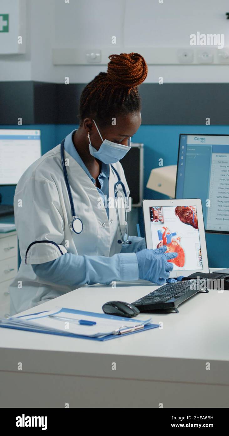 Medic with face mask pointing at tablet with heart figure for ...