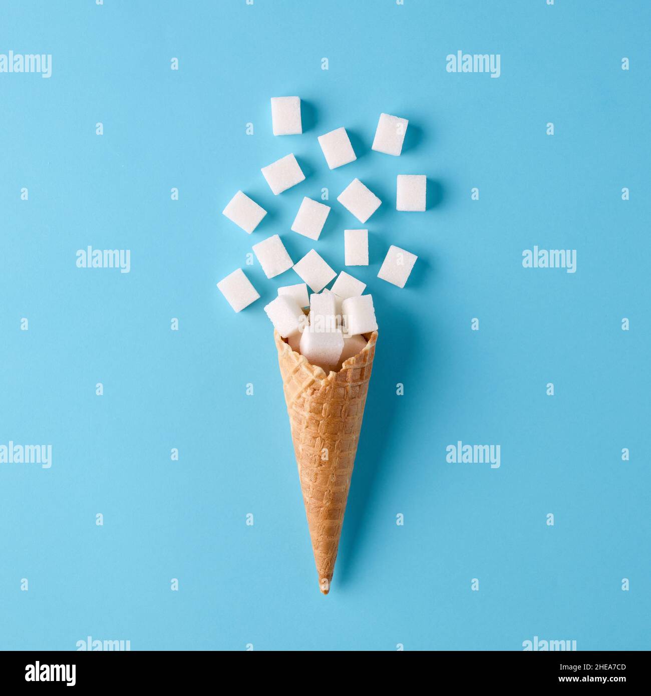 Sugar cubes on ice cream cone on blue background. Minimalistic sweet ...