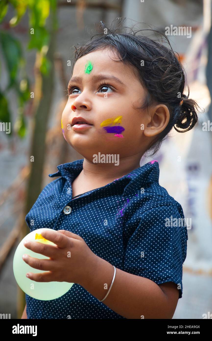 Cute boy holding water balloon during Holi Stock Photo - Alamy