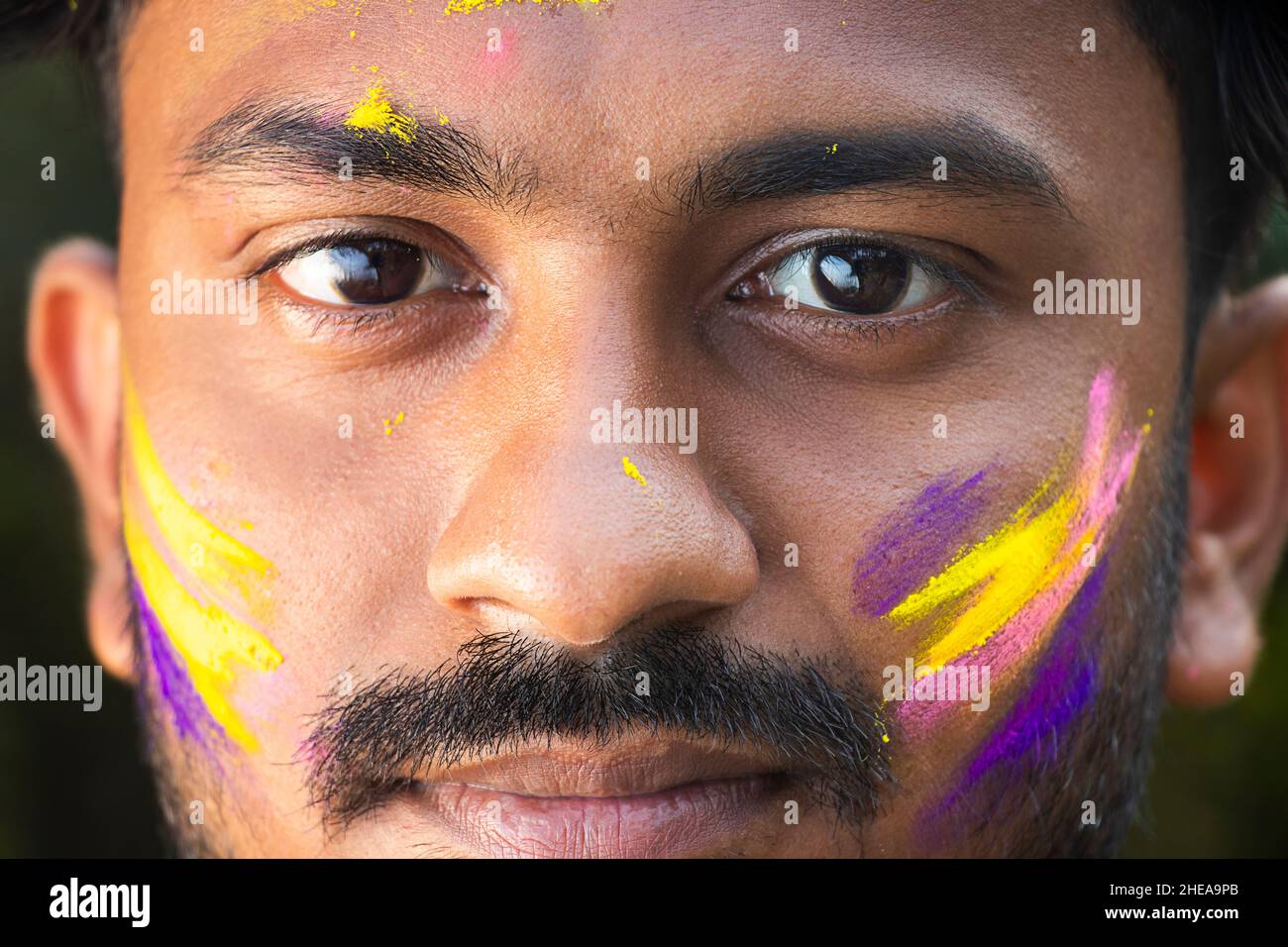 Close up of a young Indian man's eyes covered in colored dye at Holi ...