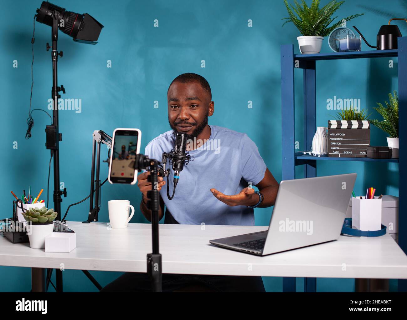 Influencer sitting down at desk with laptop in vlogging studio smiling ...