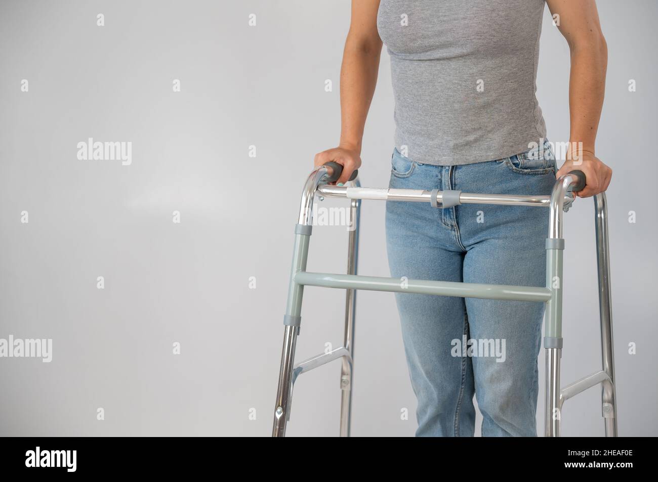 A woman is walking with a walker on a white background Stock Photo - Alamy