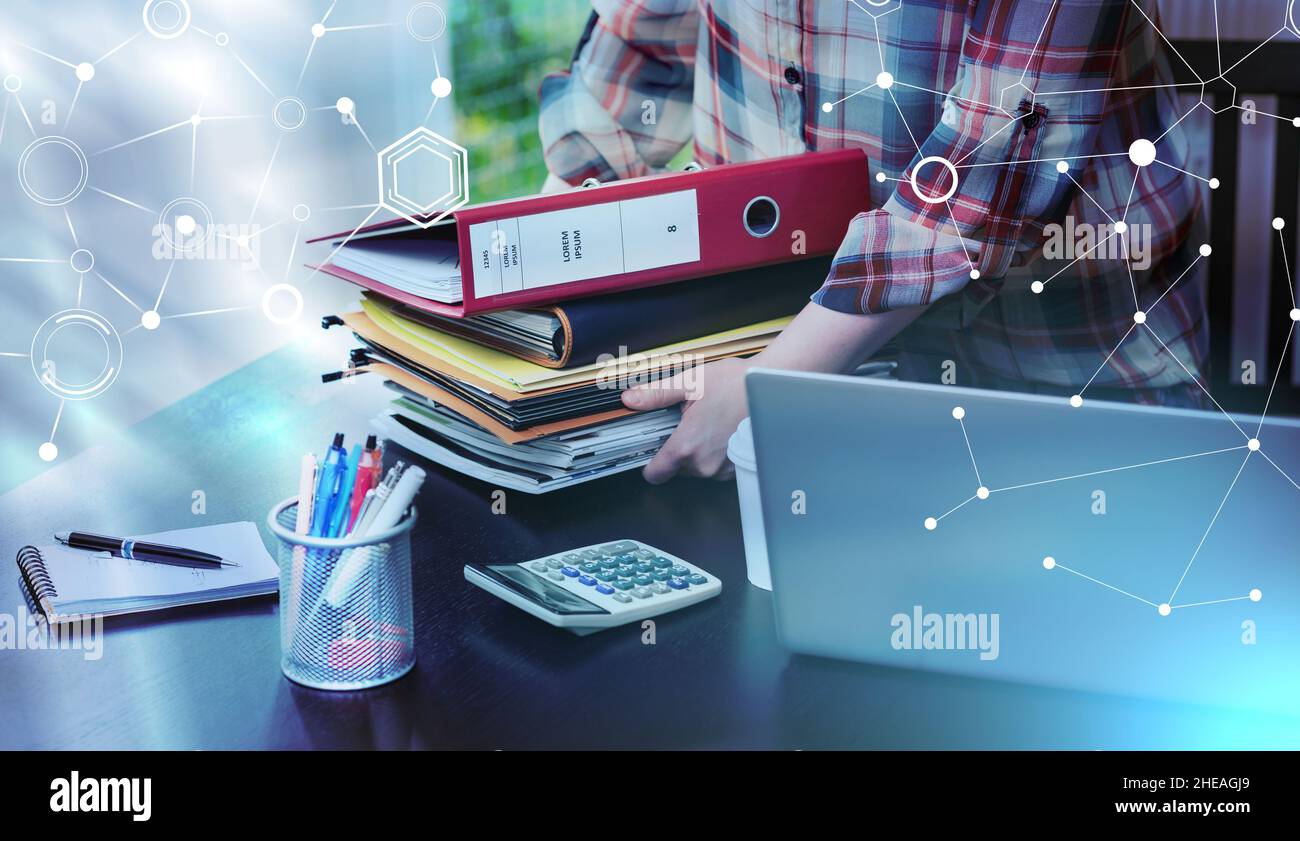 Businesswoman putting a stack of binders and folders on her desk; light ...