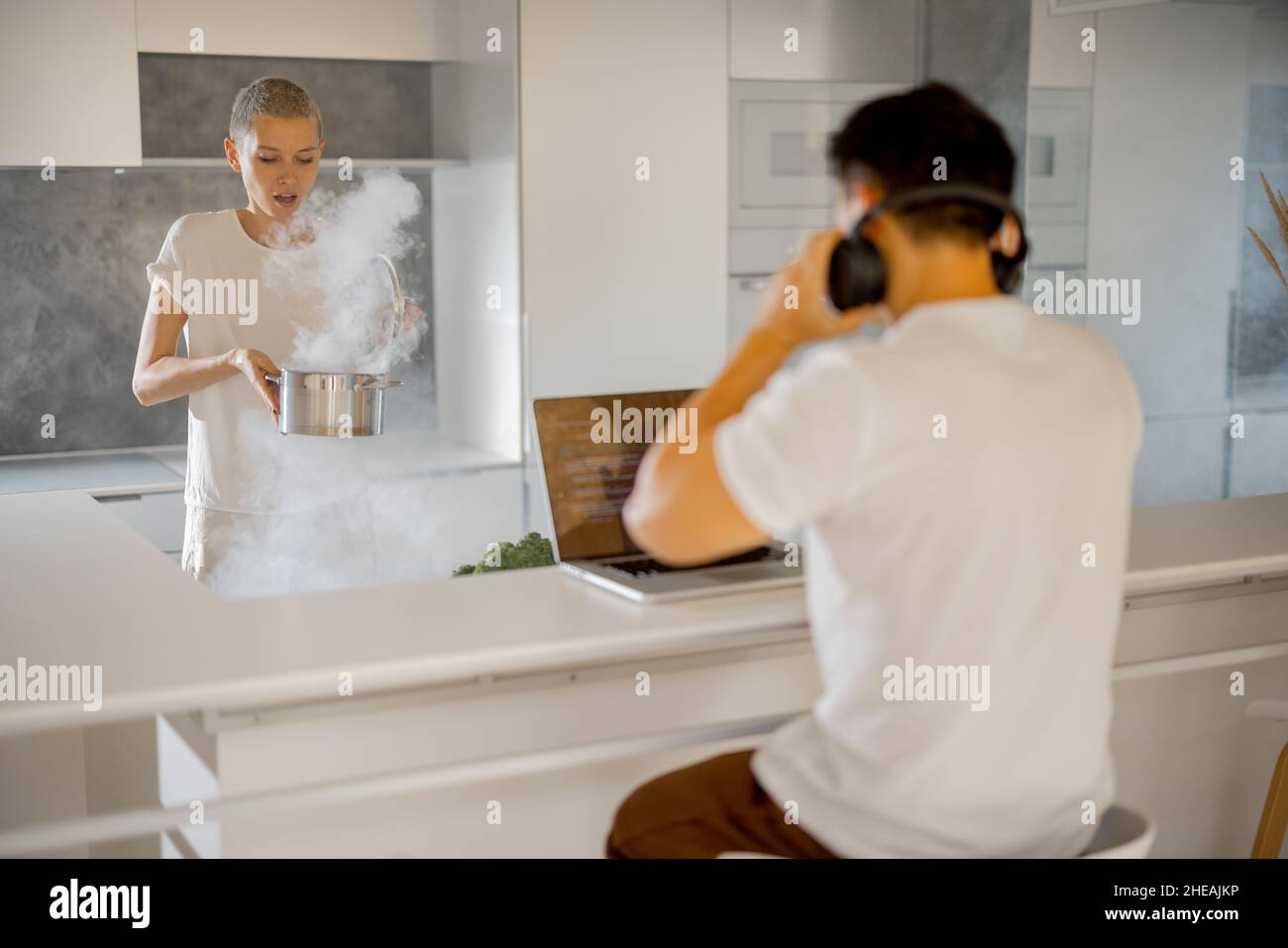 Woman cooking dish while man working Stock Photo - Alamy