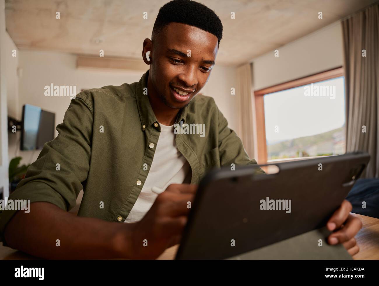 Young adult black male writing with pen on electronic tablet while ...