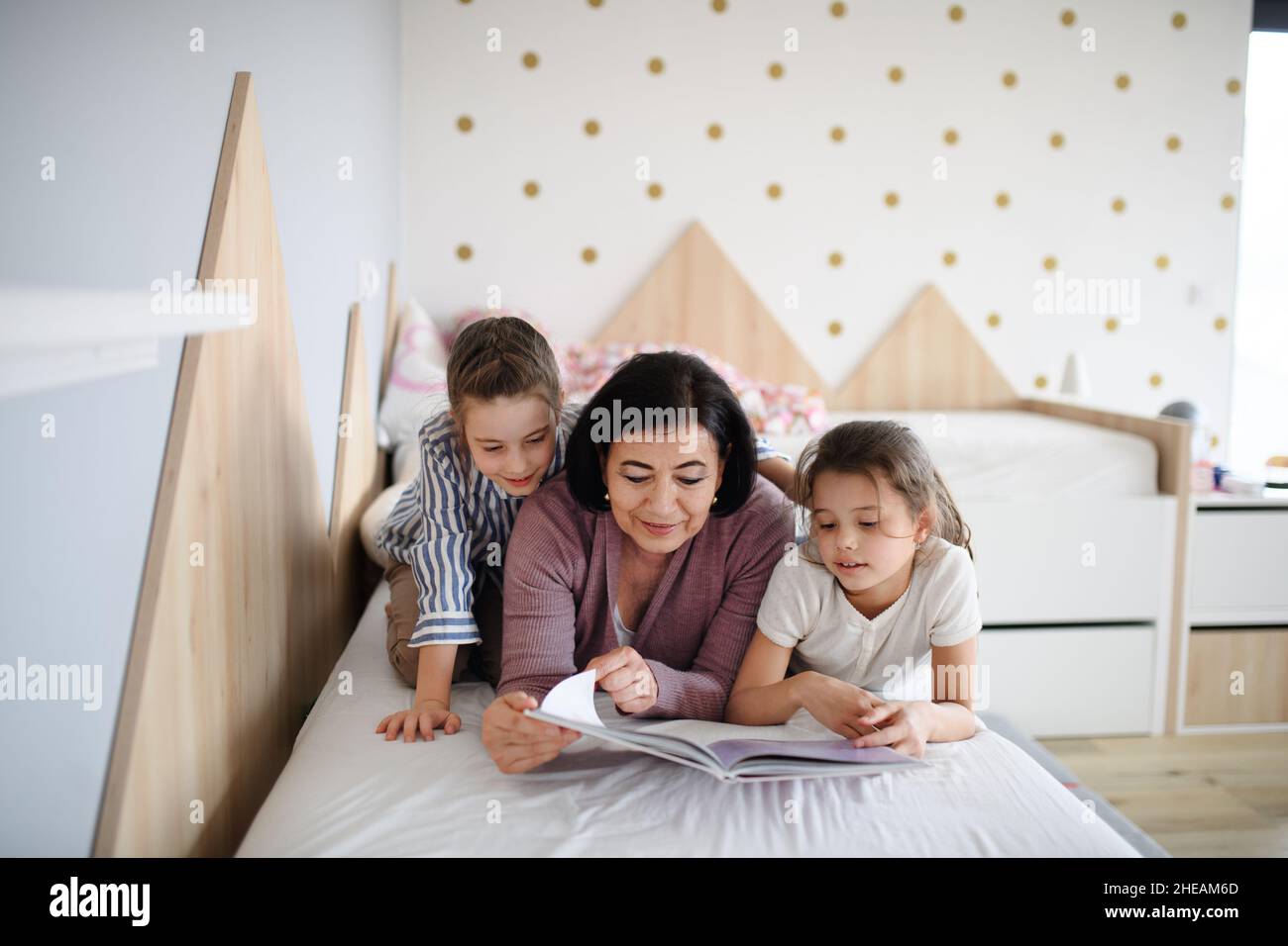 Happy small girls with senior grandmother indoors in bedroom at home ...