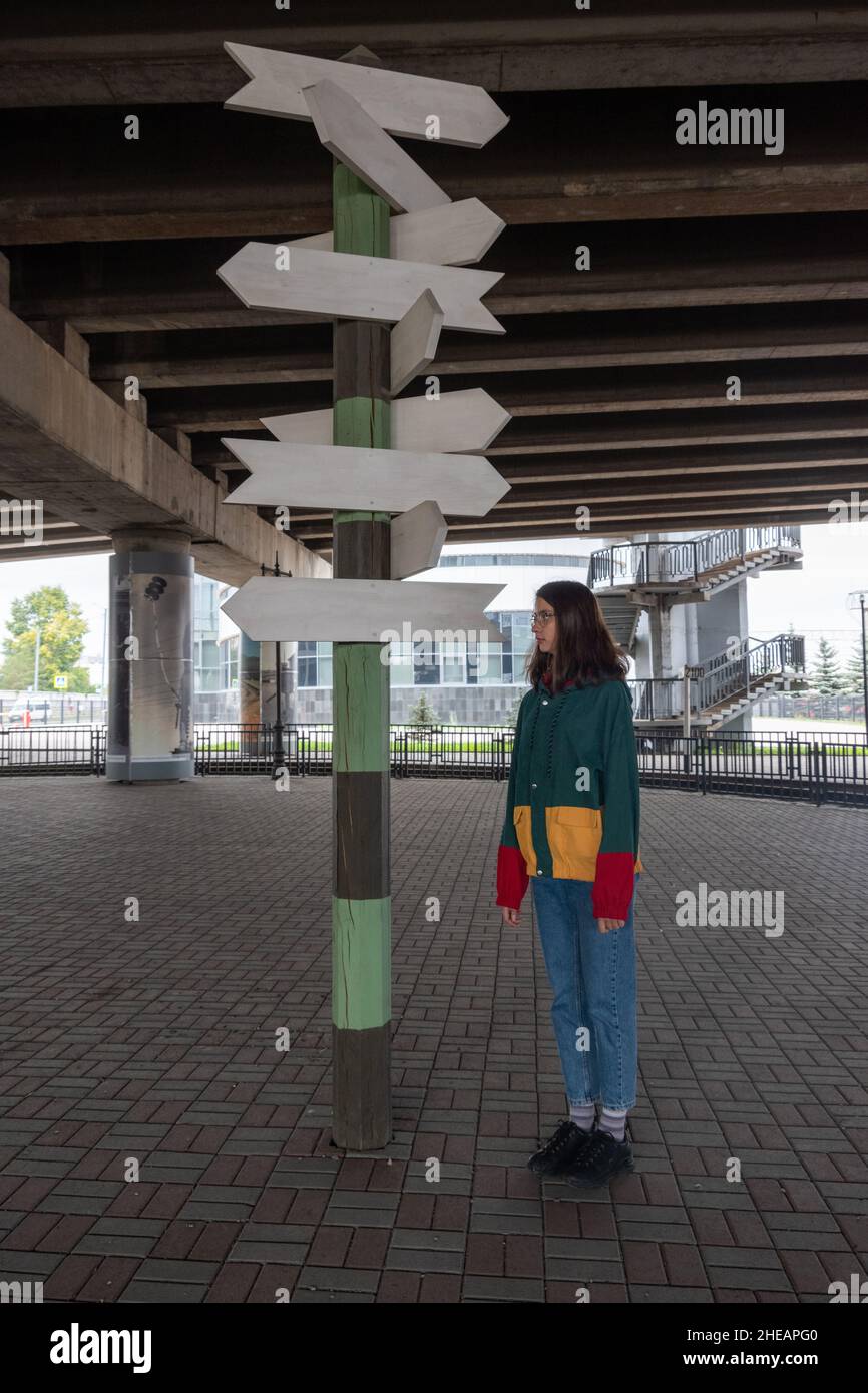 A teenage girl in multicolored trendy clothes stands confusedly near a ...