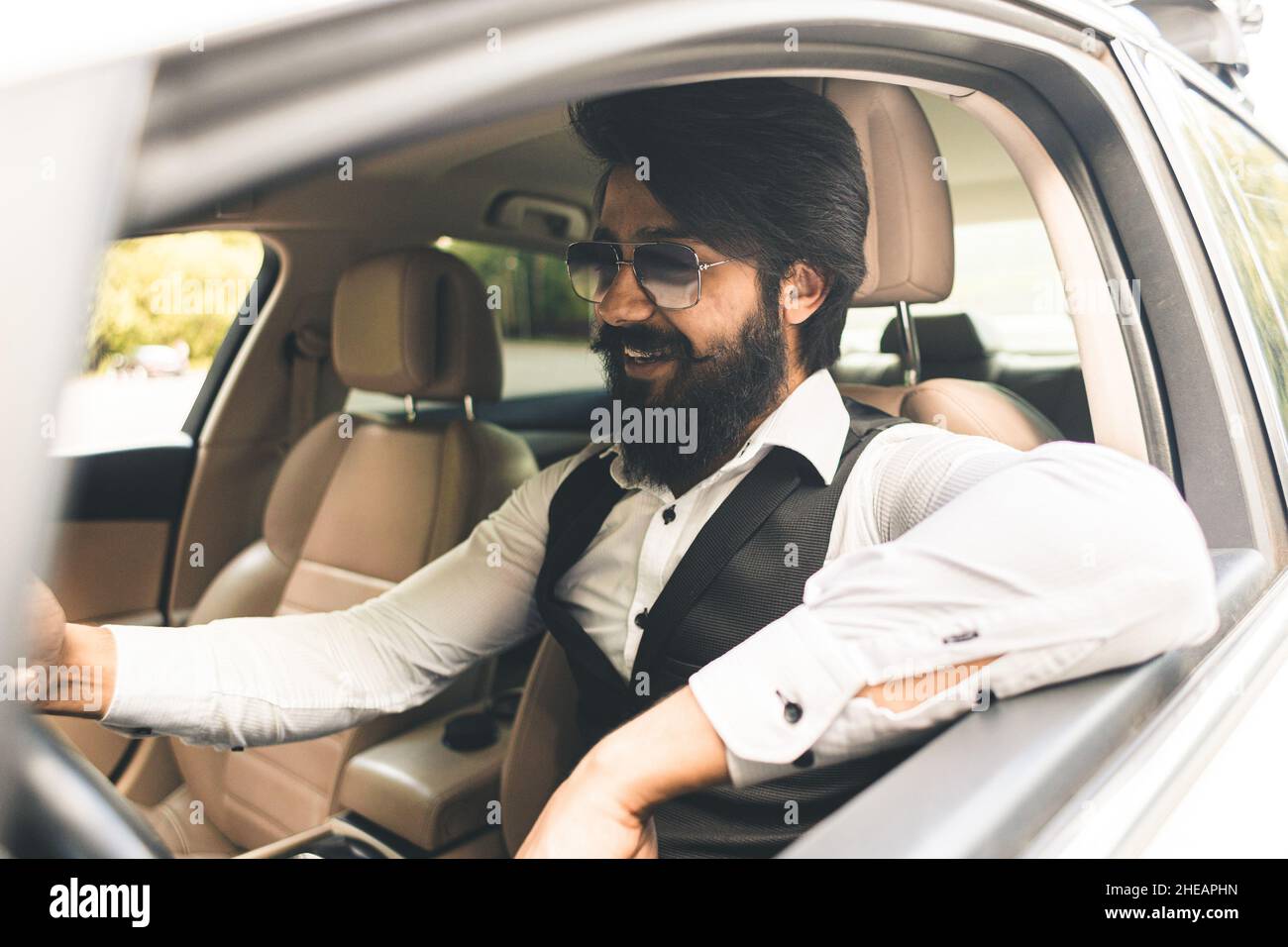 Stylish and successful Indian in a stylish suit driving a luxury car ...