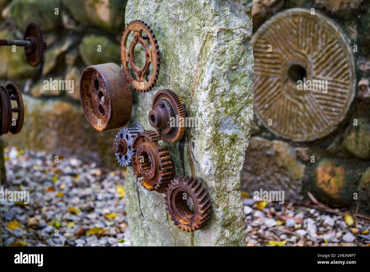 A stone in the park is inlaid with a pile of rusty gear sculptures ...