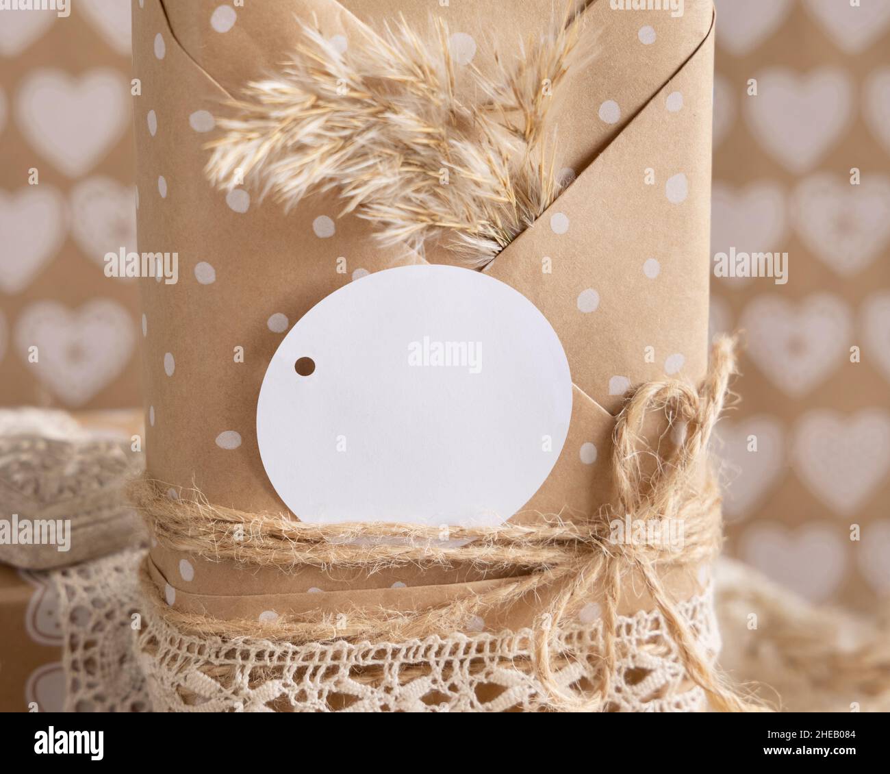Valentines kraft paper wrapped present with round gift tag near hearts ...