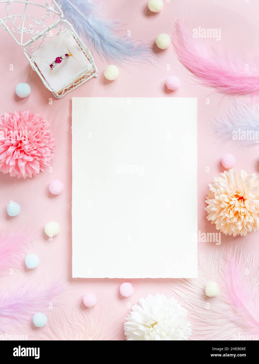 Blank Card near pastel flowers, pom-poms, feathers and ring in a gift ...