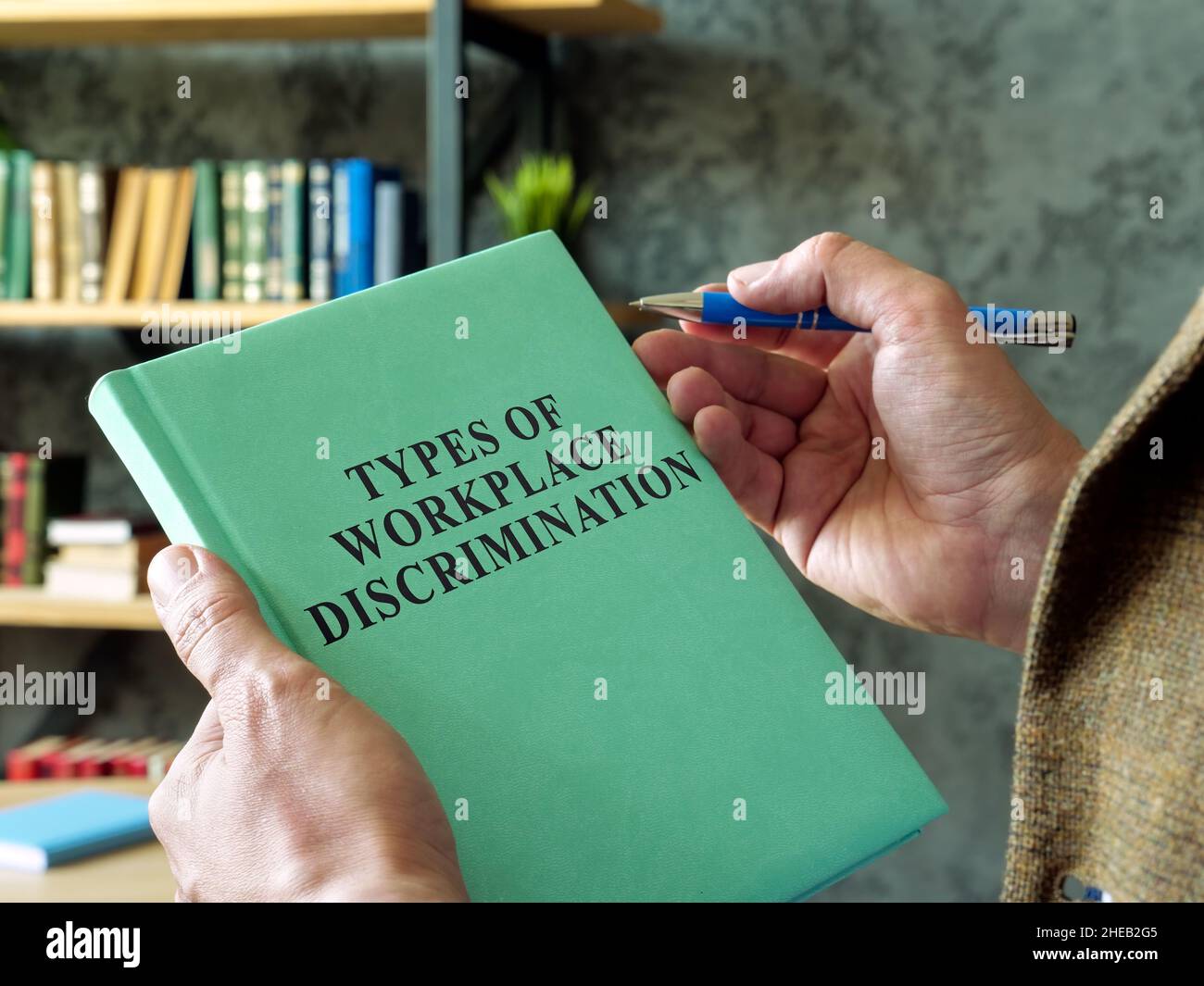 Manager holds book types of workplace discrimination Stock Photo - Alamy
