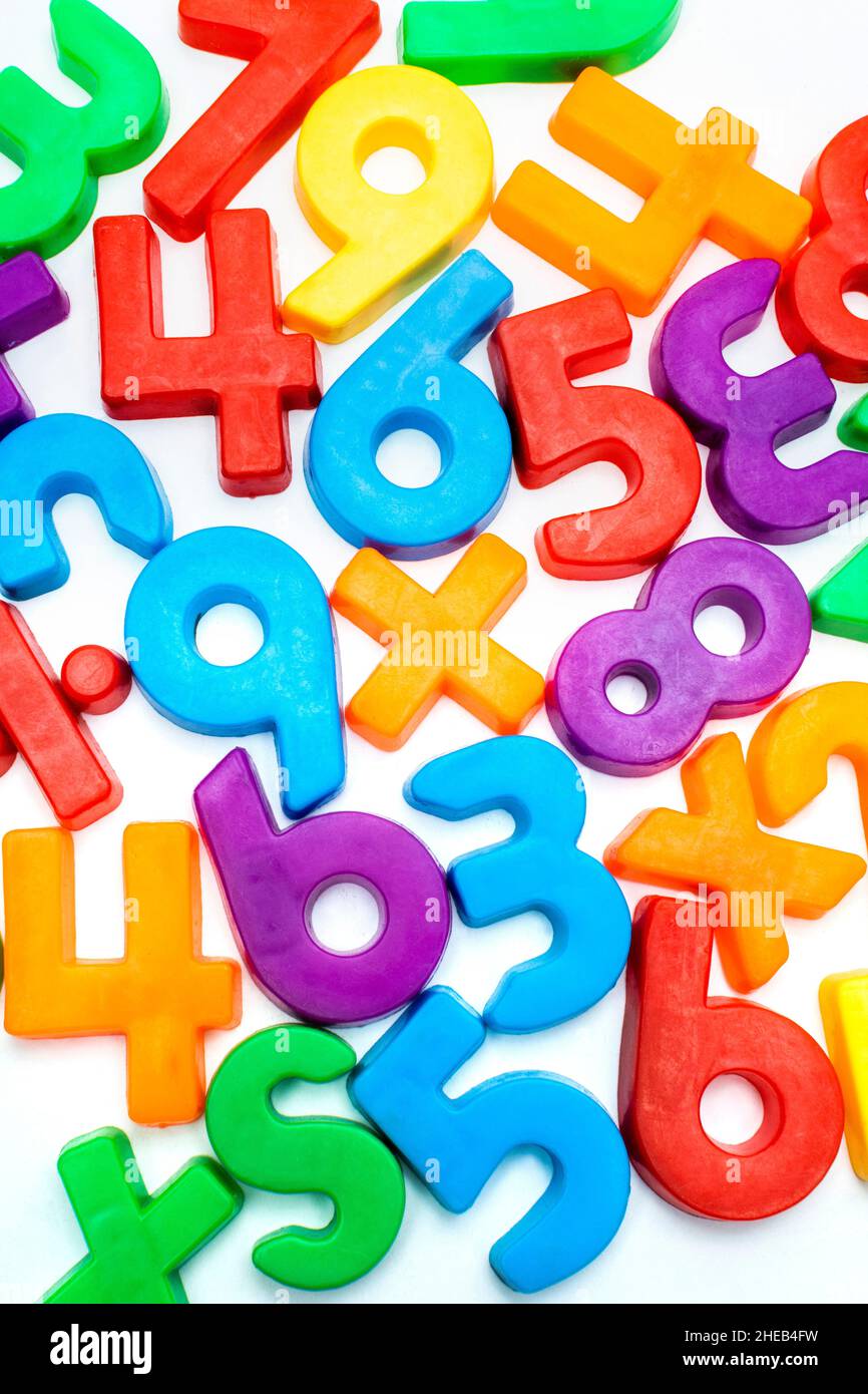 Colorful alphabet and number magnets scattered on a white surface ...