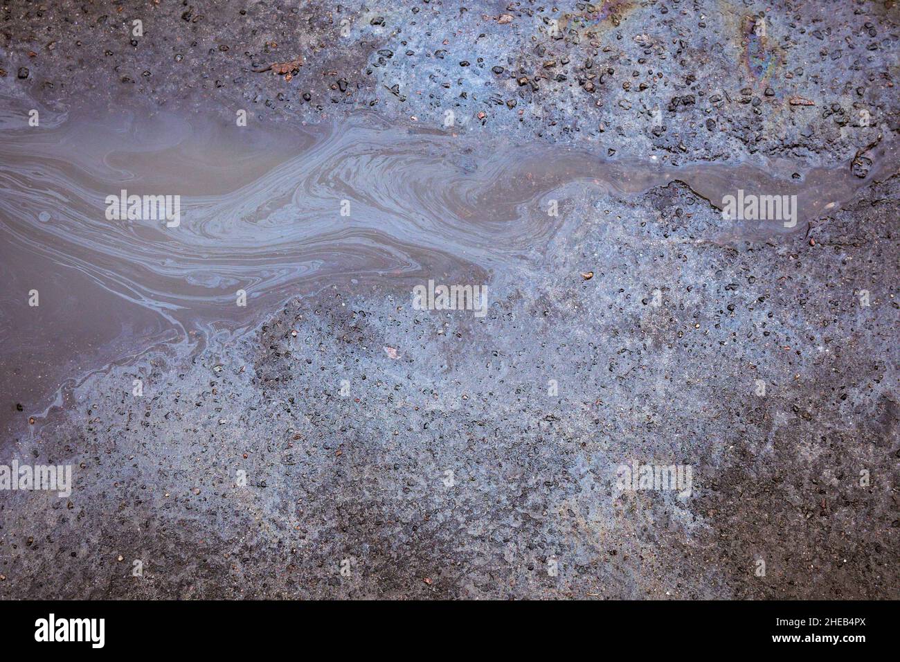 Gas stain on wet asphalt caused by a leak under a car or truck ...