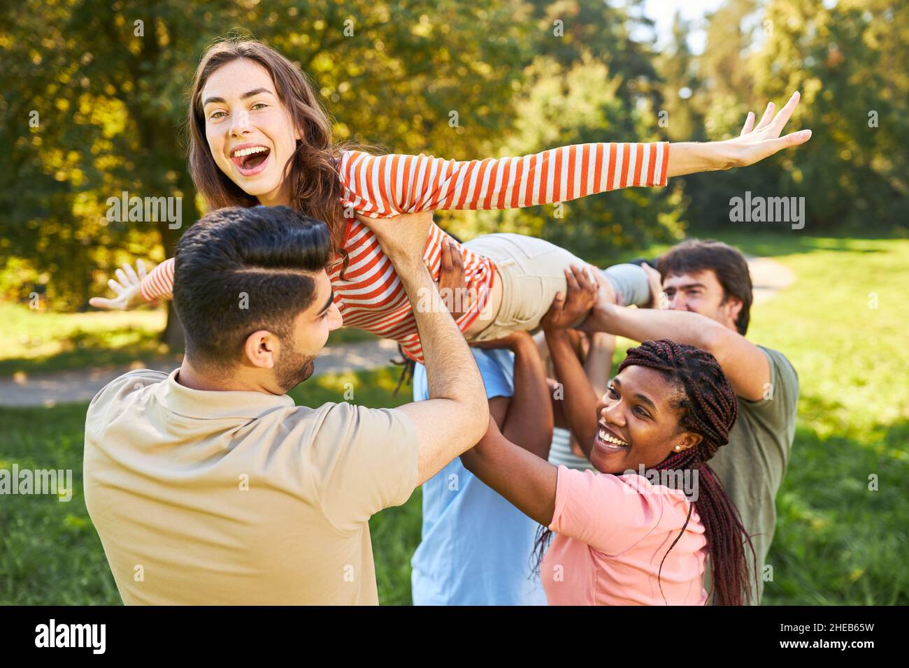 Group of friends together lifts young woman as an exercise for ...