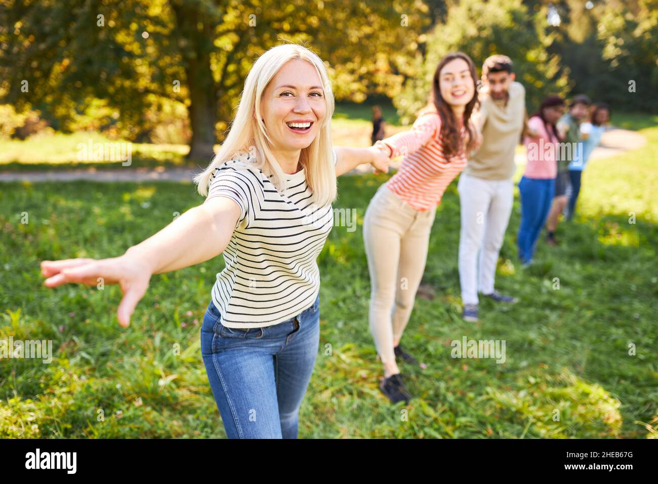 Young people in the park in summer join hands in team building workshop ...