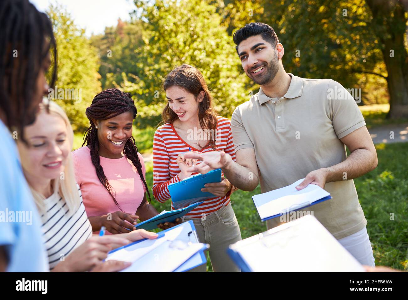 Young people in the multicultural start-up team discuss direction ...