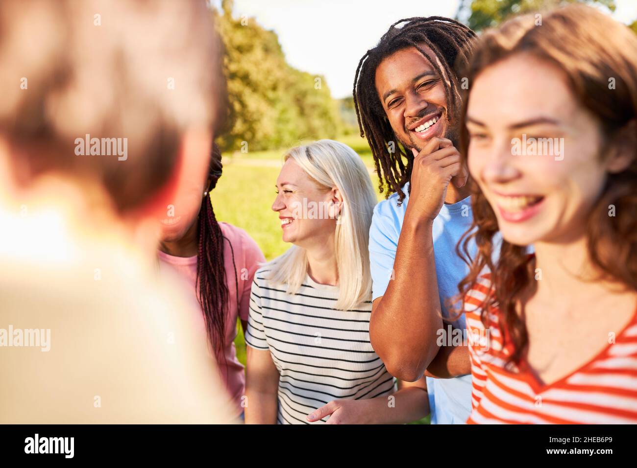 Young people as multicultural group of friends talking to each other in ...