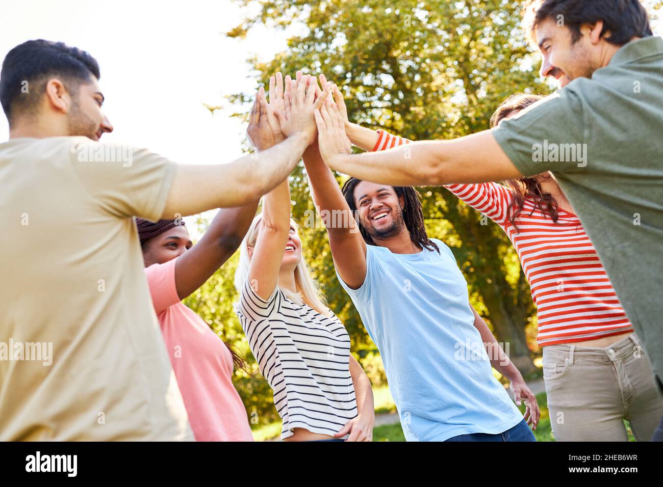 Multicultural group of young people high five for team building and ...