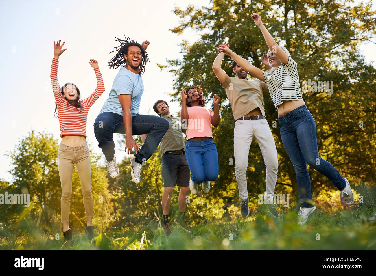 Multicultural group of young people cheering and jumping in nature in ...