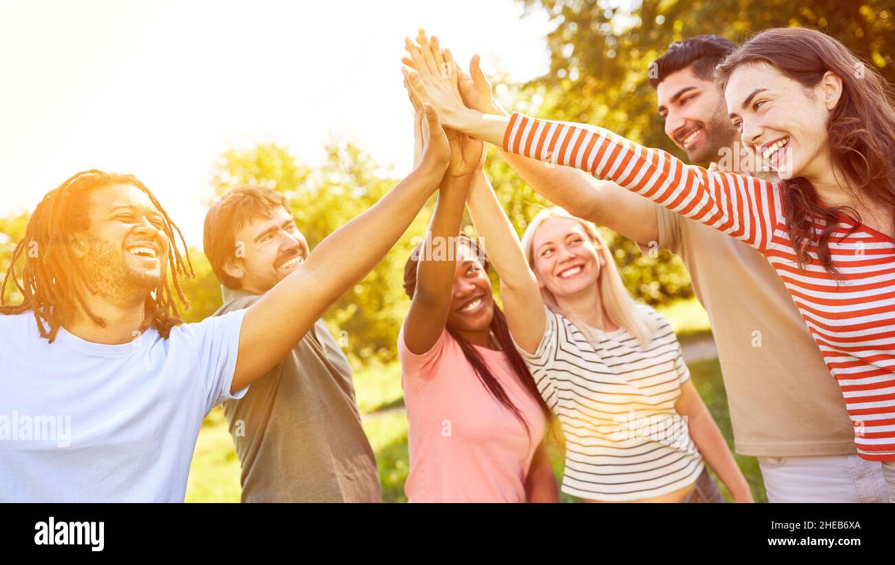 Multicultural group of laughing friends giving high five as a team ...