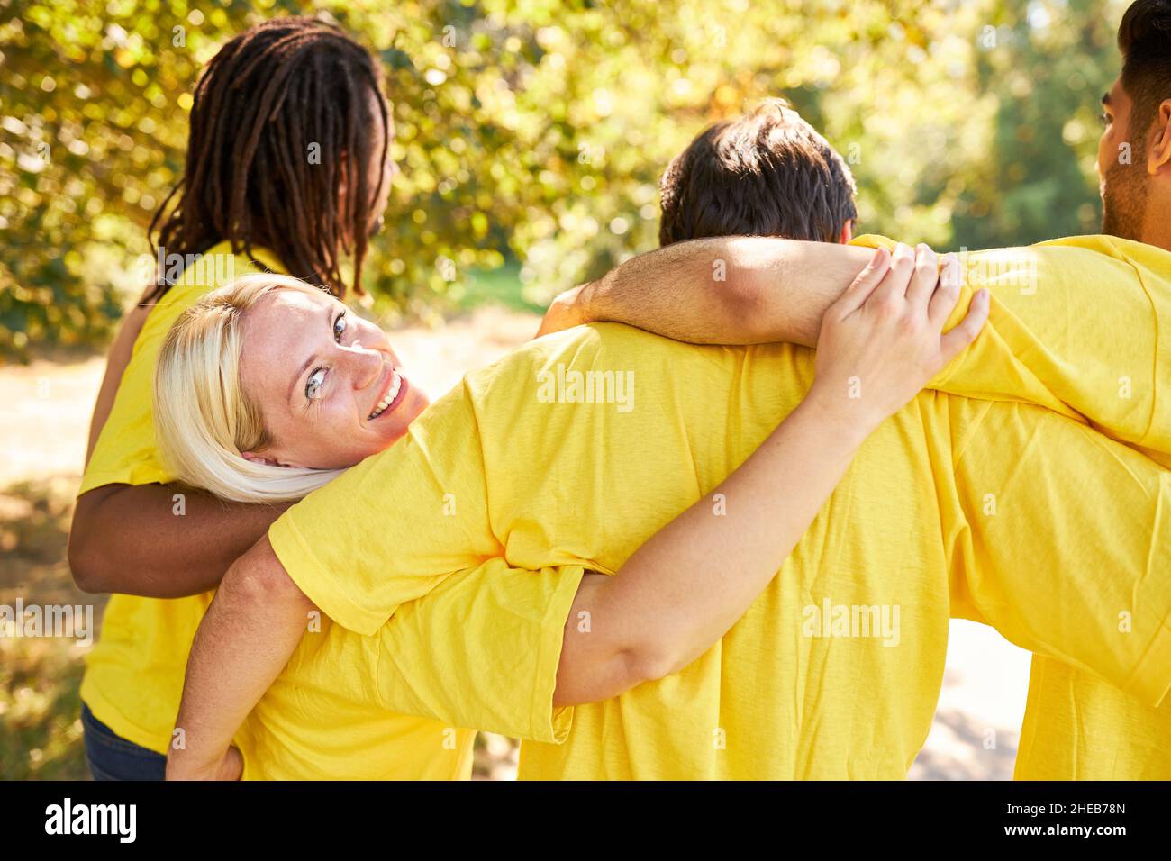 Young woman and friends hug as a team in team building workshop in ...